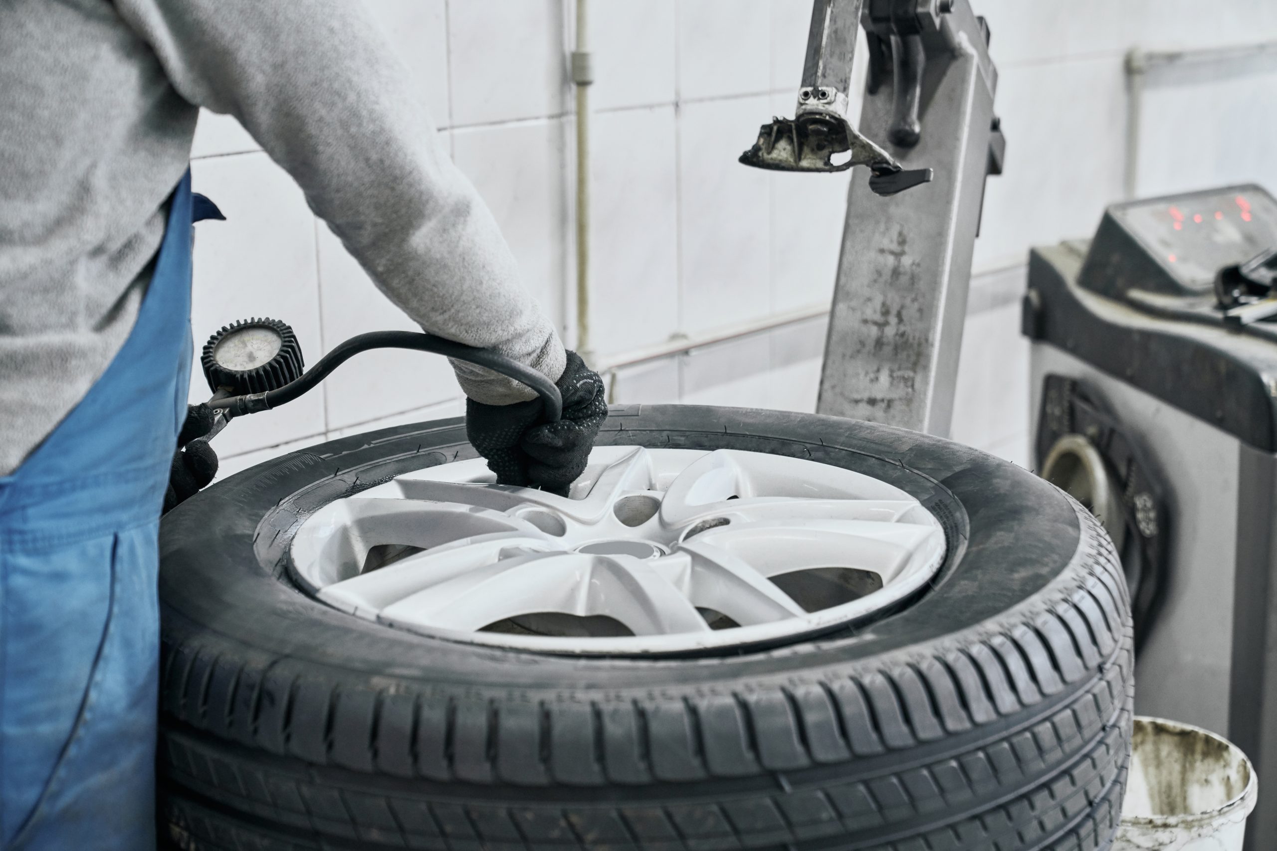 Auto mechanic inflating tire and checking air pressure | Susllantas
